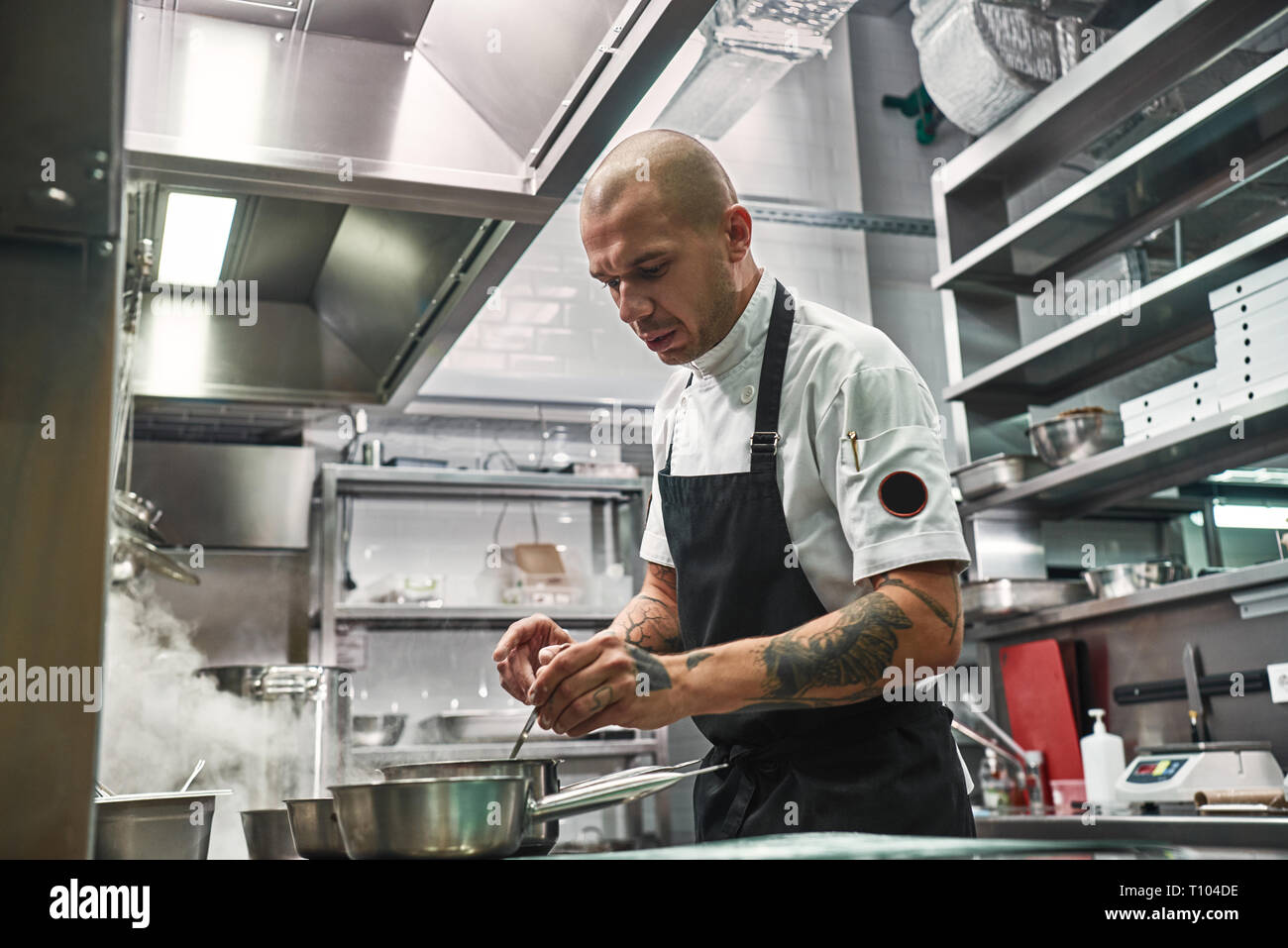 Important moment. Serious professional chef in apron, with several ...