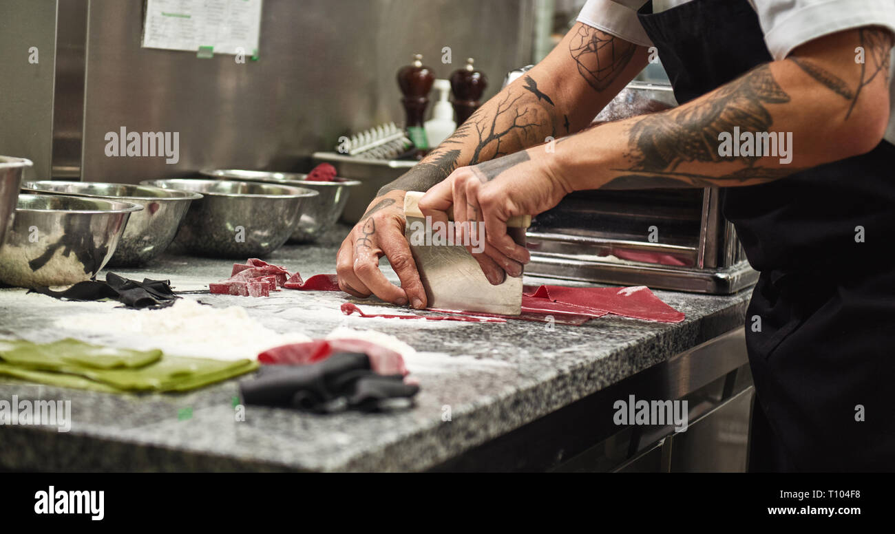 Making pasta process. Close up photo of chef's hands with tattoos ...