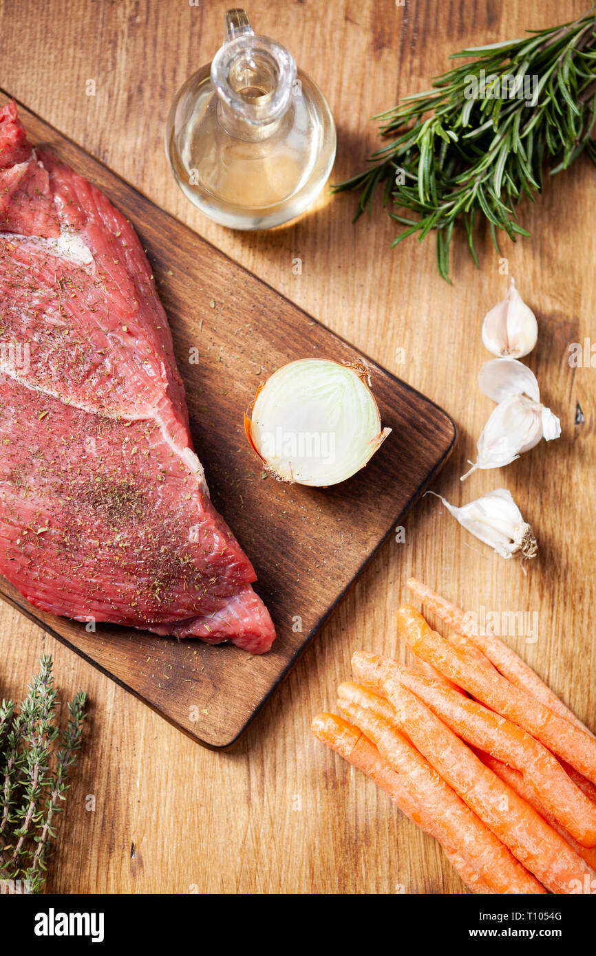 Top view of raw meat on cutting board seasoned with rosemary. Raw ...