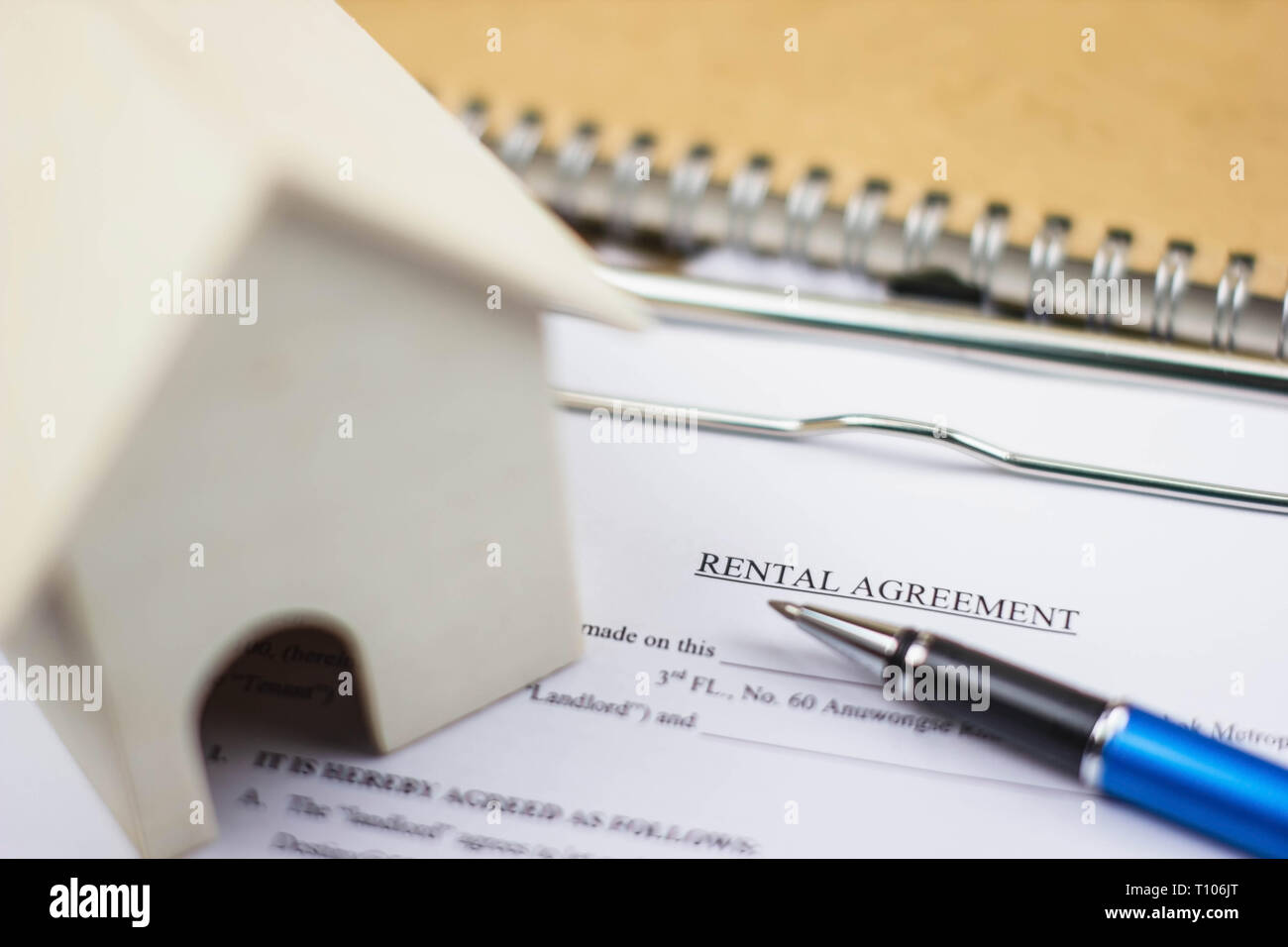 Home model and rental agreement document with pen. Depicts the lease ...