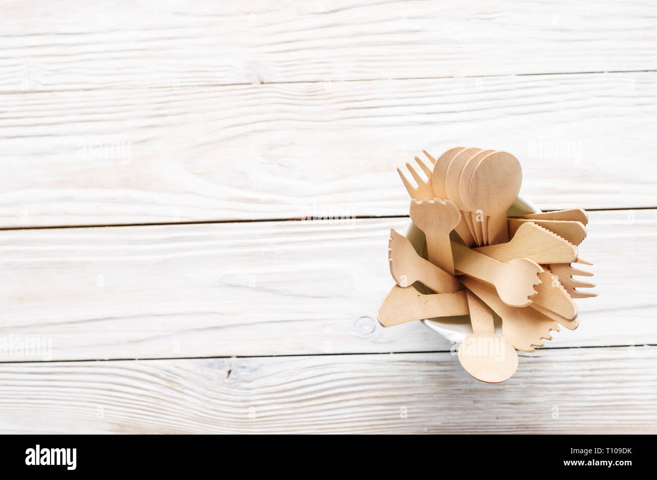 Wooden single use kitchenware in paper cup on white table. Top view ...