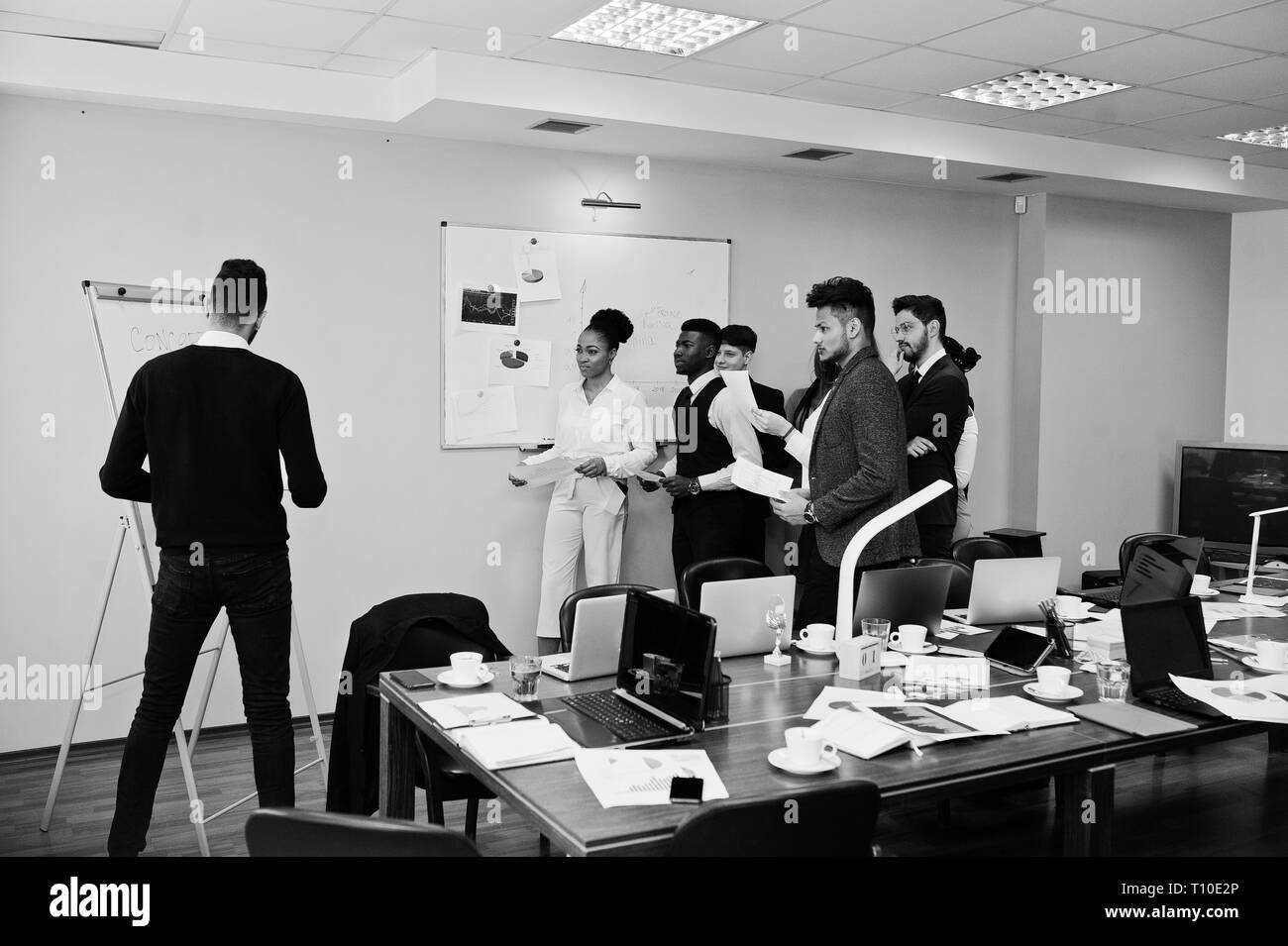 Mixed race business coach presenting report standing near whiteboard ...