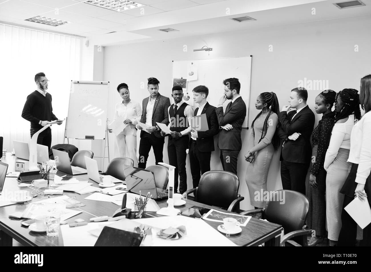 Mixed race business coach presenting report standing near whiteboard ...