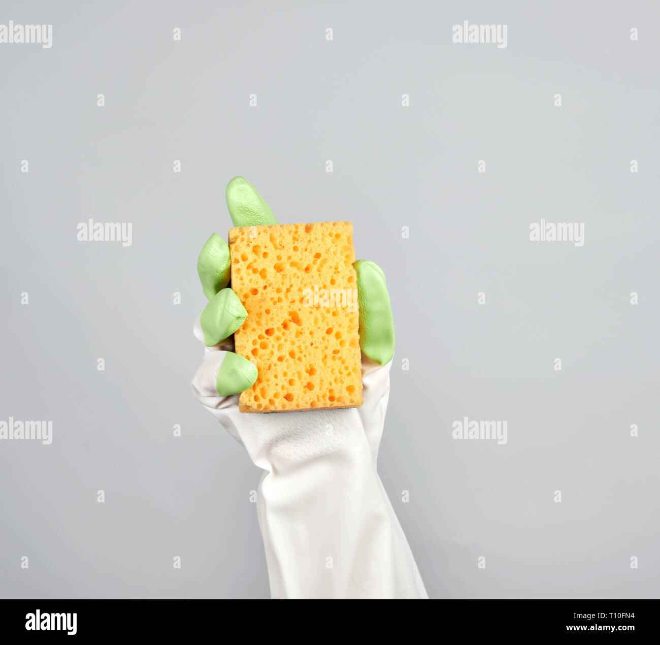 gloved hand holds yellow kitchen sponge, white background Stock Photo ...