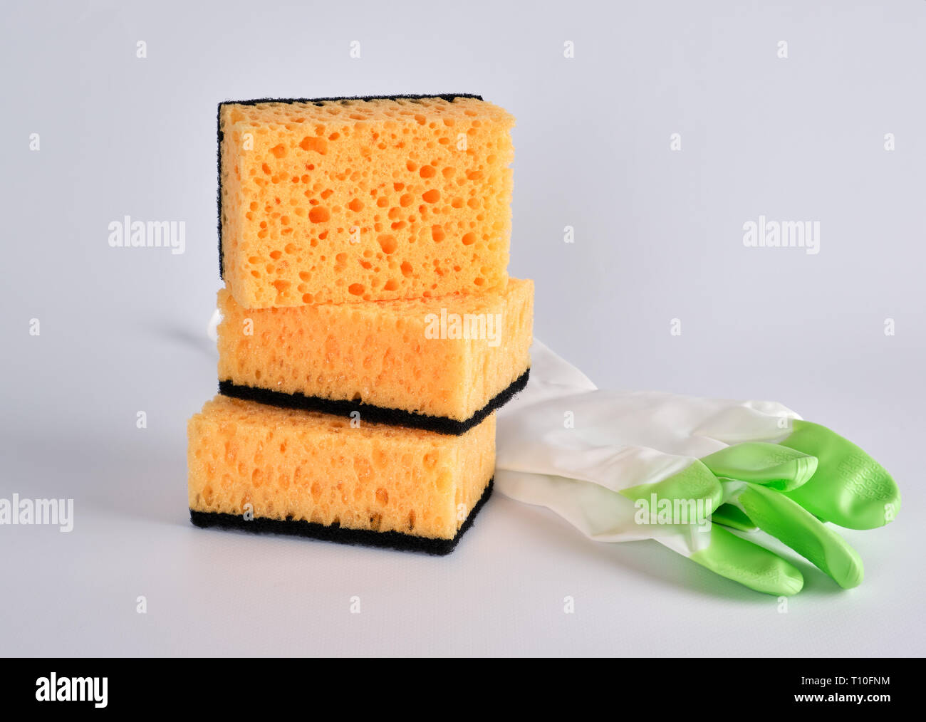 stack of yellow kitchen sponges for washing dishes and gloves on a ...