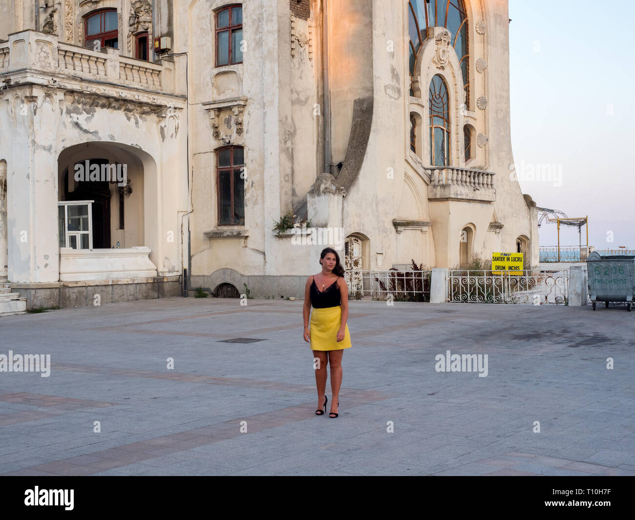 A woman wearing a yellow skirt poses for a photo next to the derelict ...
