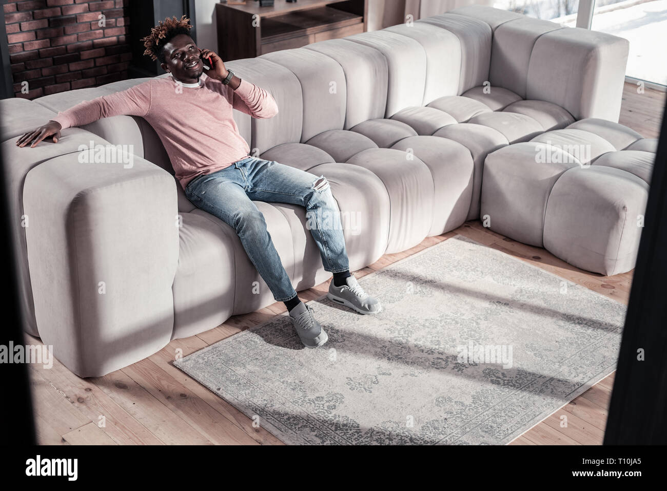 Relaxed international male person sitting on sofa Stock Photo - Alamy