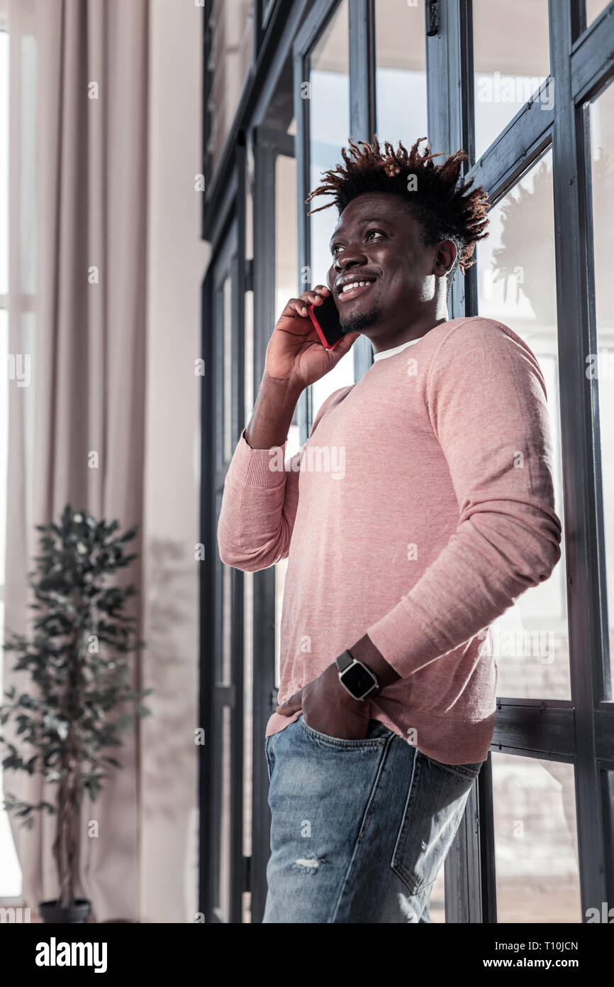 Positive delighted international man leaning on window Stock Photo - Alamy