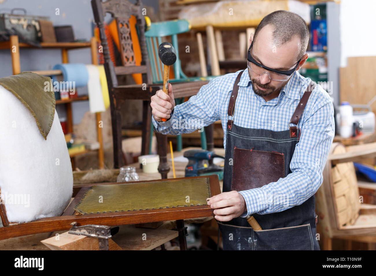 Qualified workman upholstering chair in repair furniture workshop Stock ...