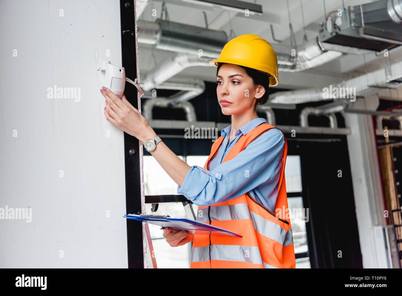 beautiful firefighter checking fire alarm while holding clipboard Stock ...