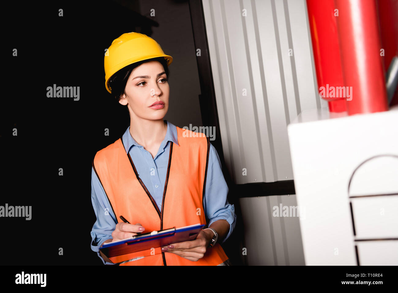 beautiful female firefighter holding clipboard and standing near fire ...