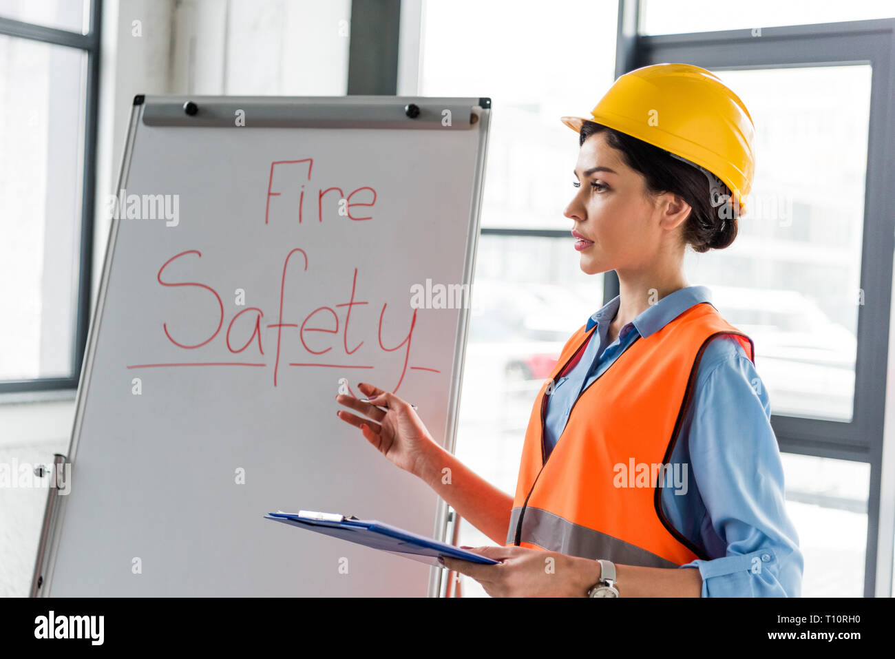 female firefighter in helmet holding clipboard and pen while talking ...
