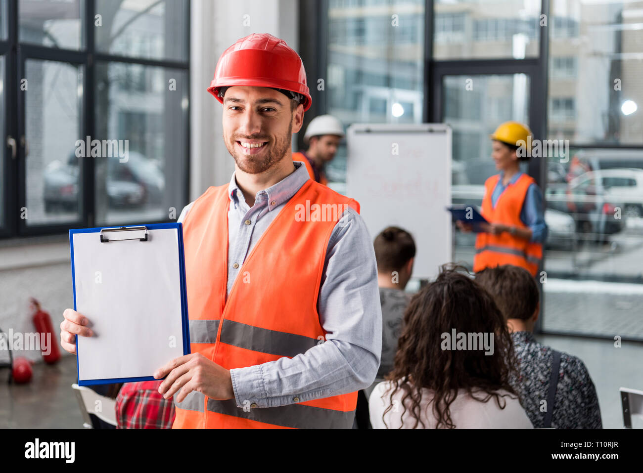 cheerful fireman holding blank clipboard near coworkers giving talk on ...