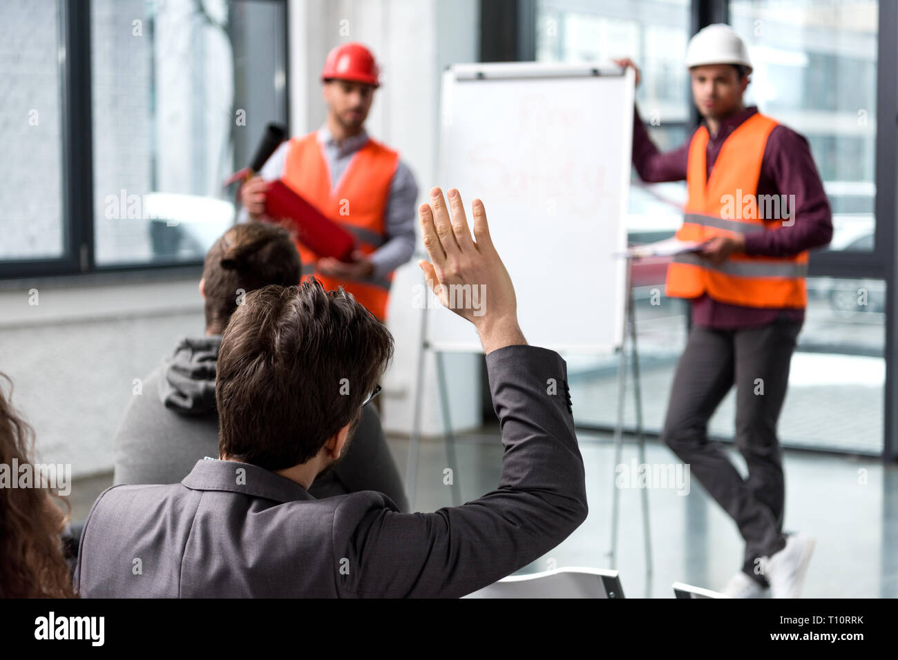 selective focus of man raising hand near handsome firemen in helmets ...