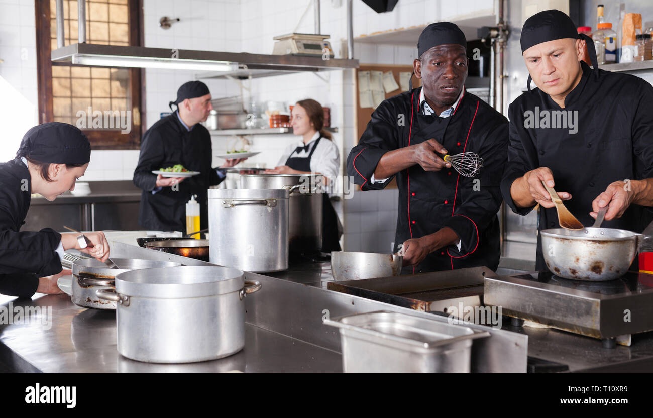 Positive cooks in process of working in kitchen of restaurant Stock ...