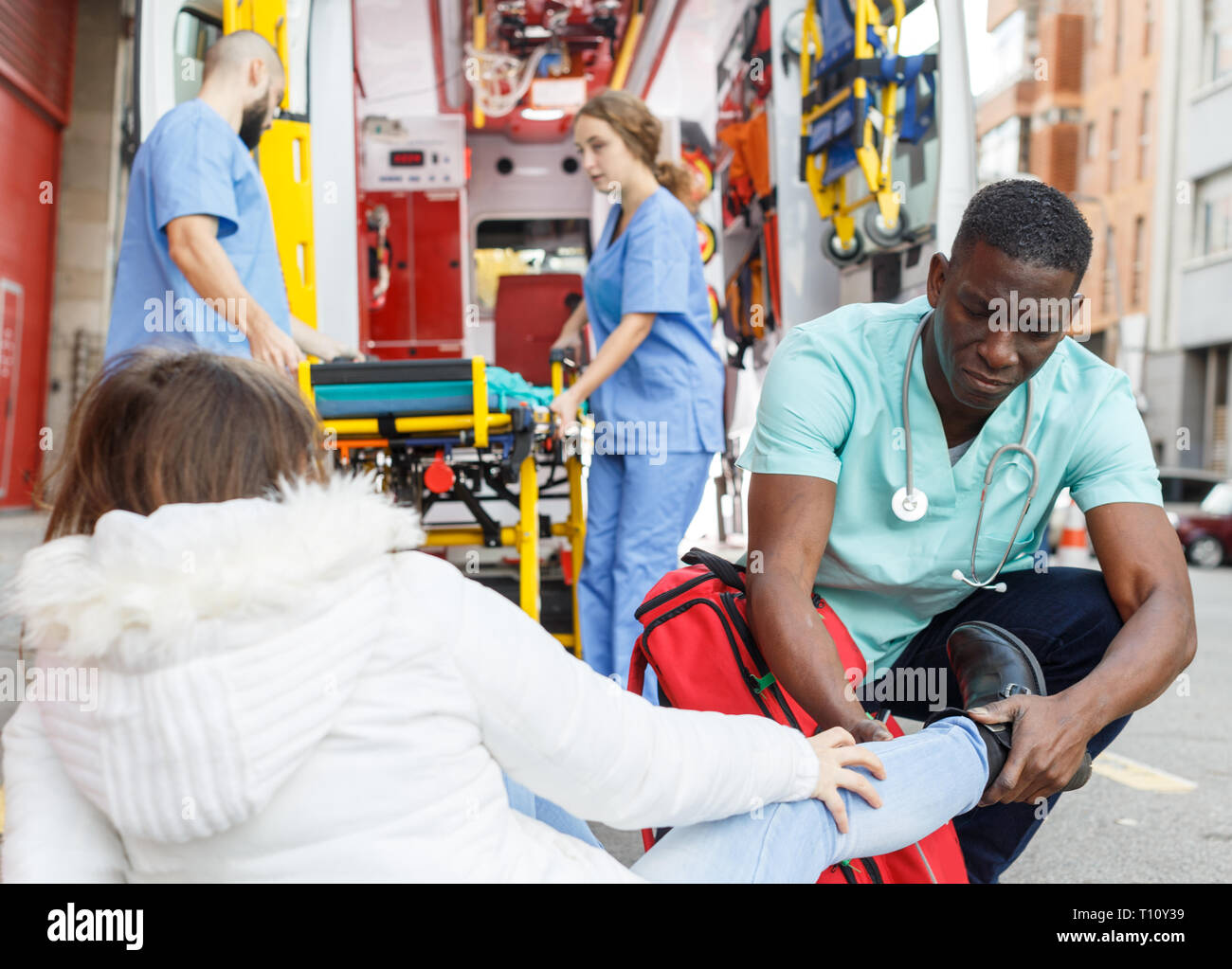 Paramedic team providing first aid to woman with injured leg Stock ...