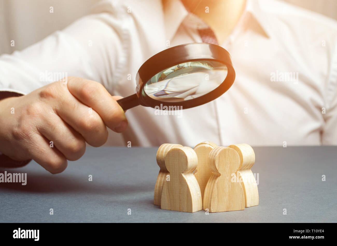 Business leader holding a magnifying glass over a team of workers. The ...