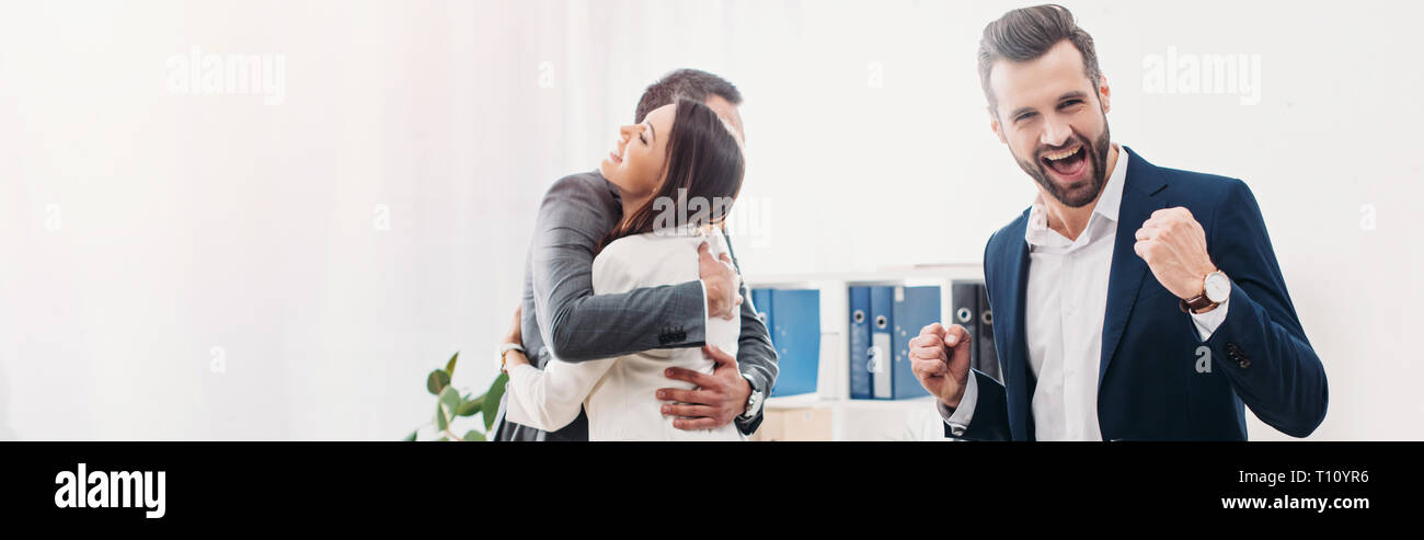colleagues hugging, smiling and celebrating in office Stock Photo - Alamy