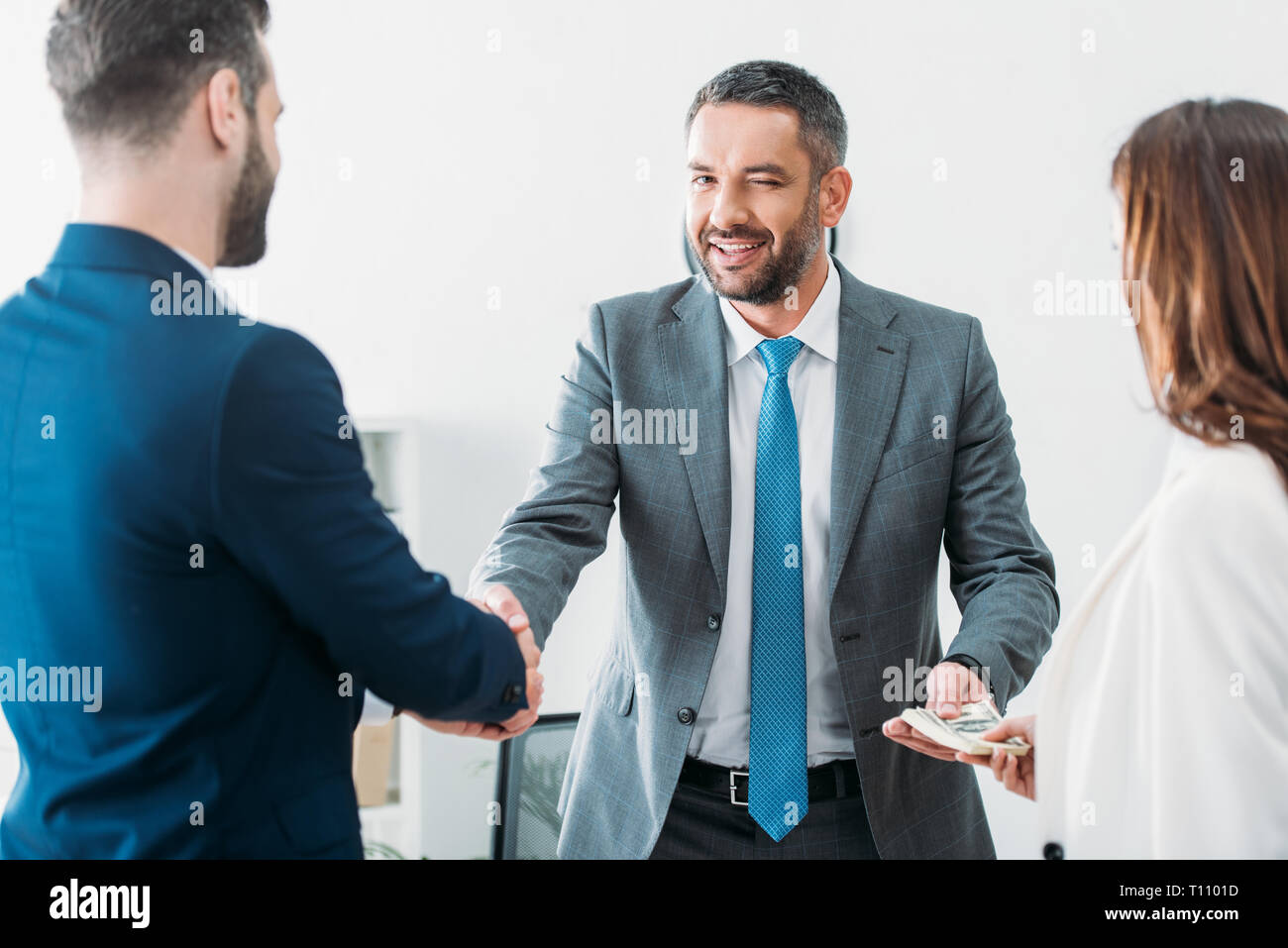 selective focus of advisor shaking hands with investors and taking ...