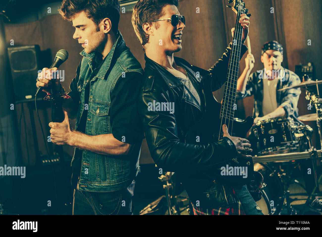 selective focus of stylish man singing near guitarist playing electric ...