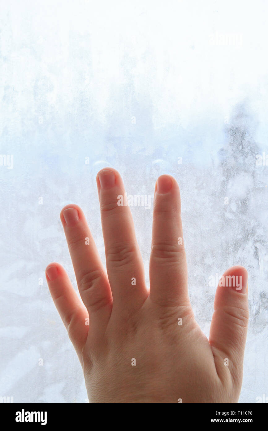 Hand on frozen winter cold window with patterns Stock Photo - Alamy