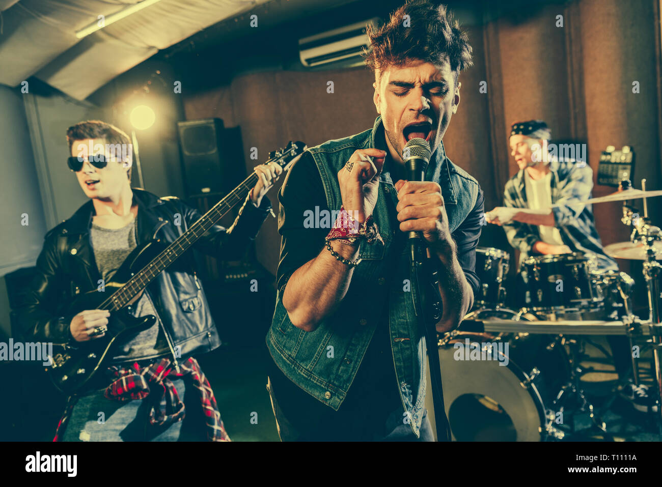 selective focus of singer singing in microphone near guitarist in ...