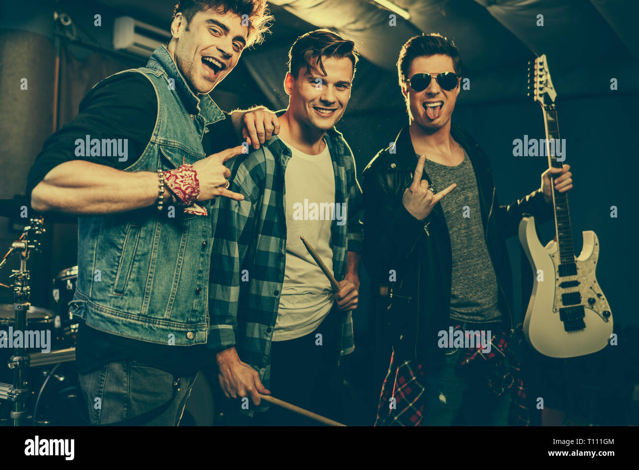 handsome and cheerful rock band smiling while showing rock signs Stock ...