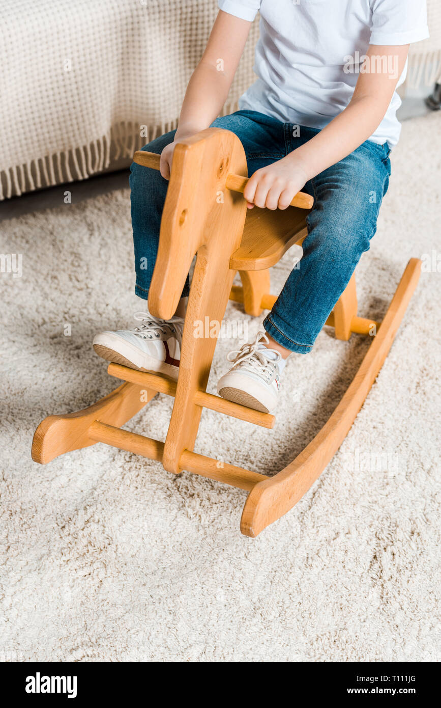 cropped view of preschooler boy riding rocking horse at home Stock ...