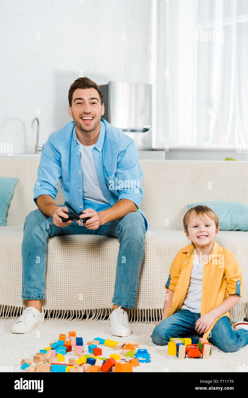 handsome smiling father playing video game while cute preschooler son ...