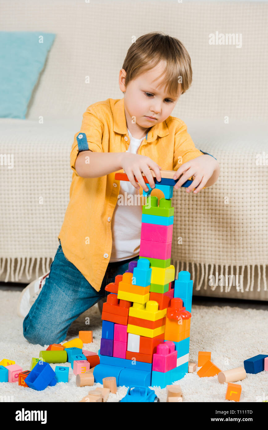 adorable preschooler boy playing with colorful building blocks at home ...