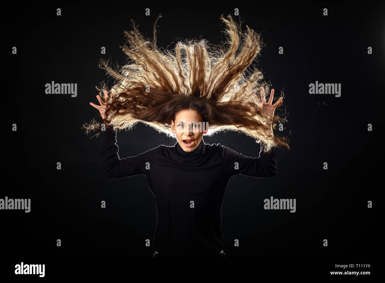 Emotional portrait of a girl with long curly hair on a black background ...