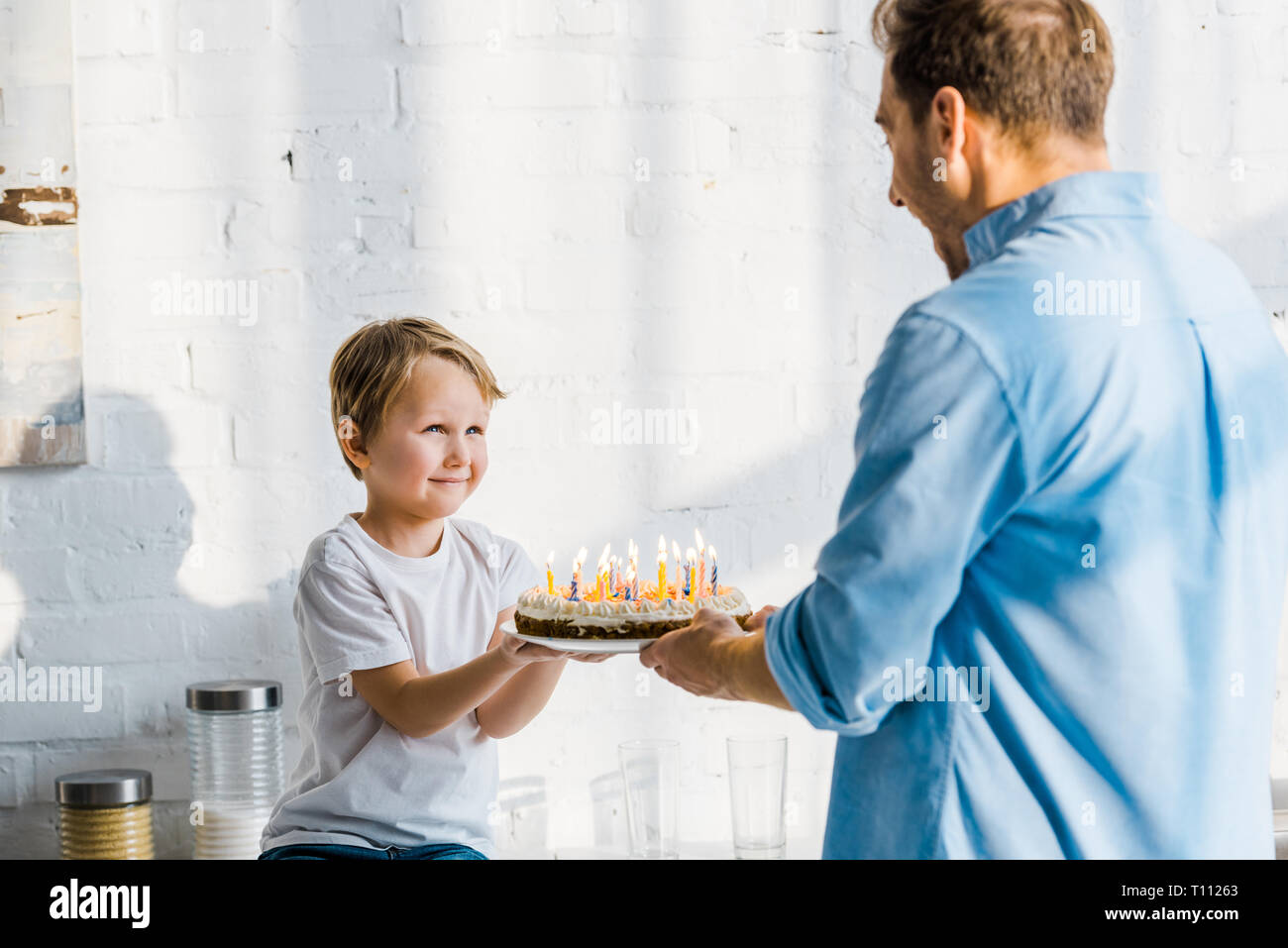father giving birthday cake to adorable preschooler son in kitchen ...