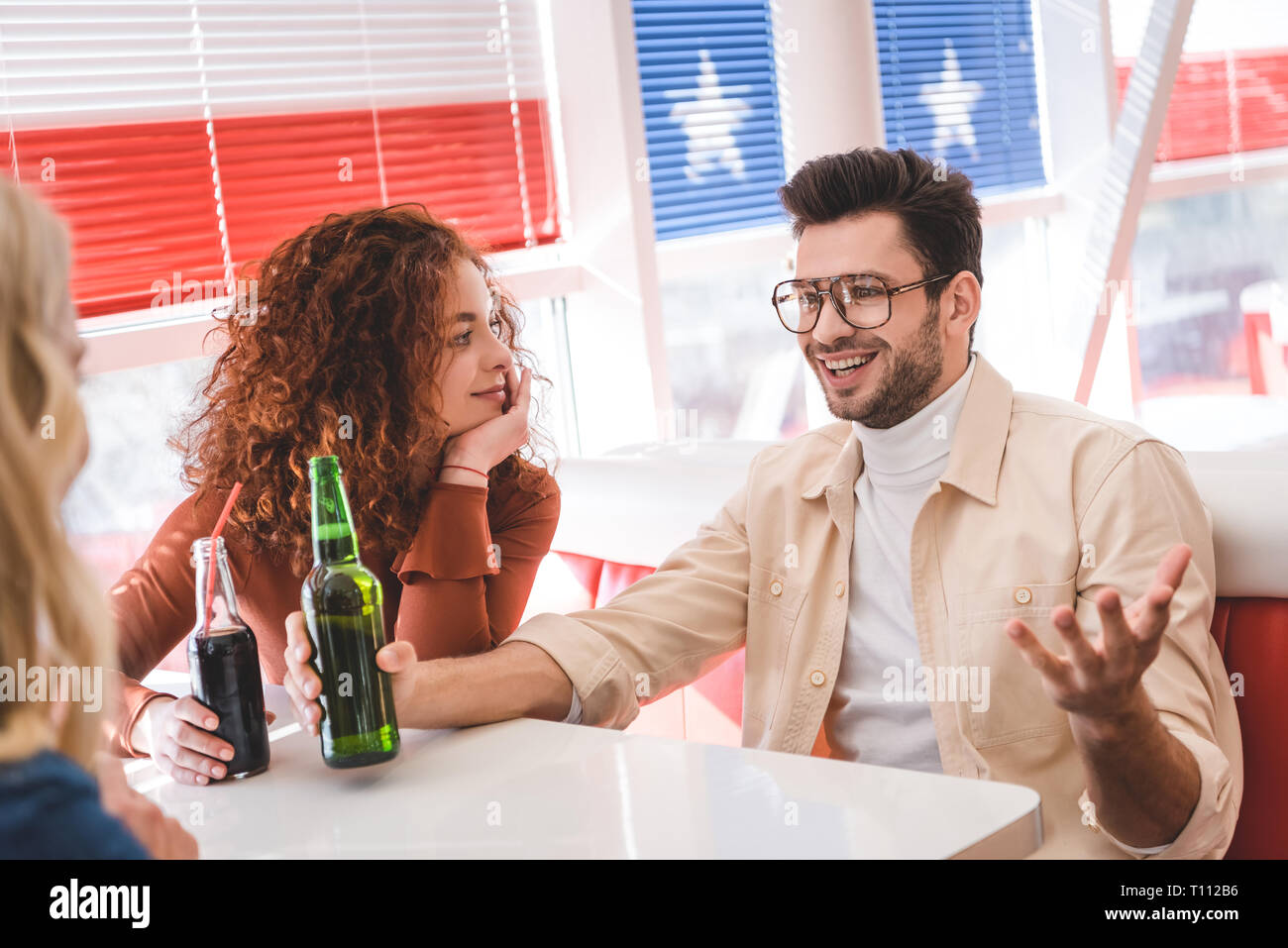 beautiful and handsome friends holding glass bottles with drink and ...