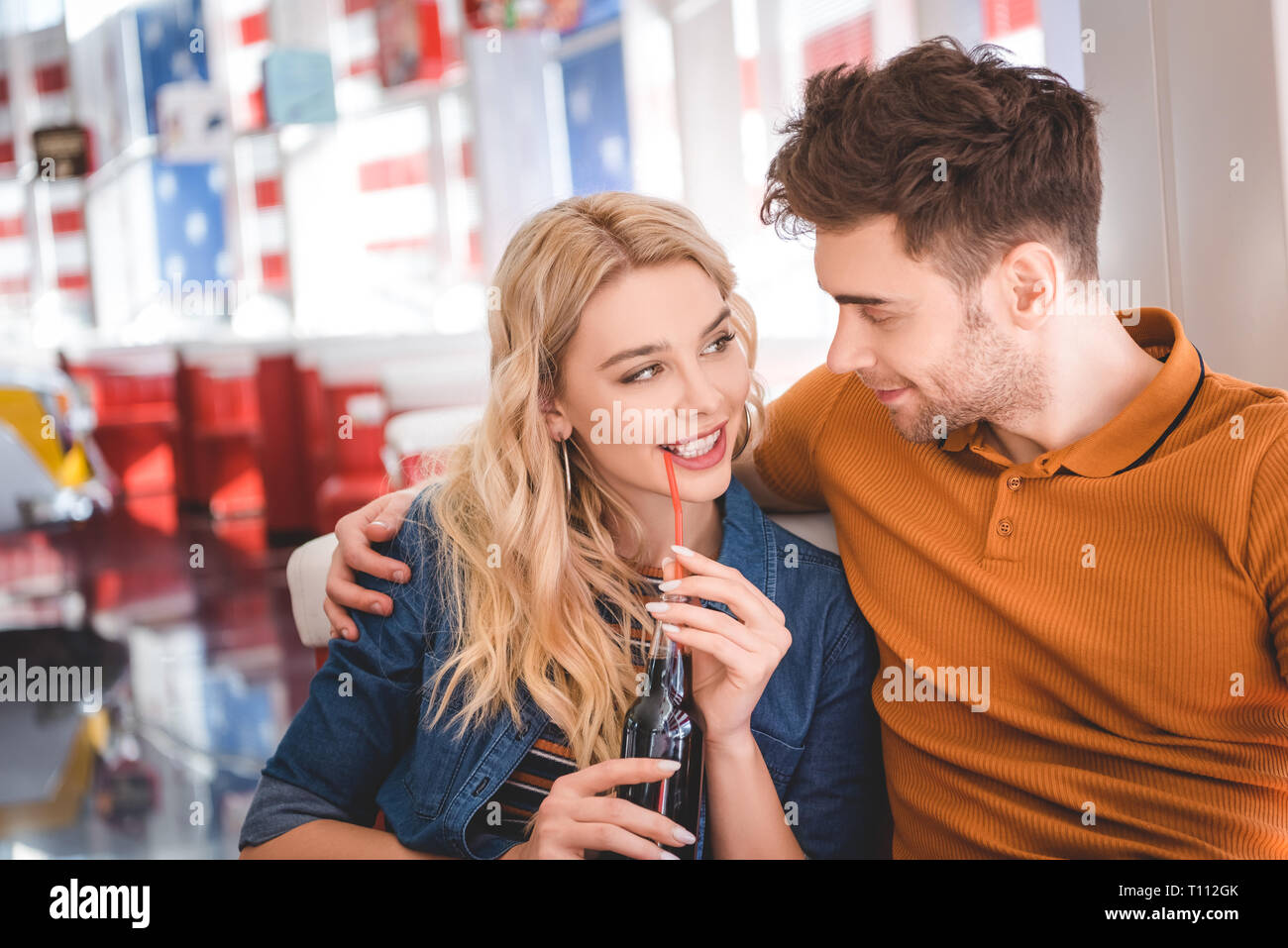 beautiful woman holding glass bottle with soda and hugging with man at ...