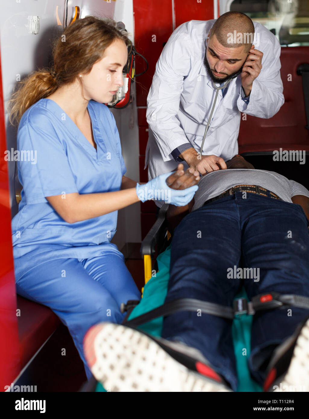 Ambulance team providing medical care to patient on stretcher in ...