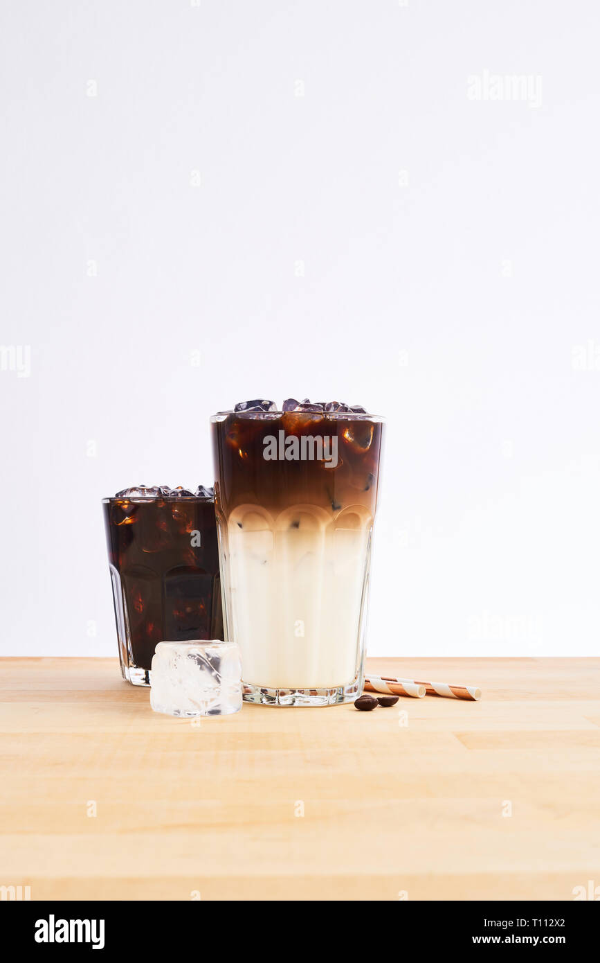Iced coffee and latte macchiato in tall glass with straws on wooden ...