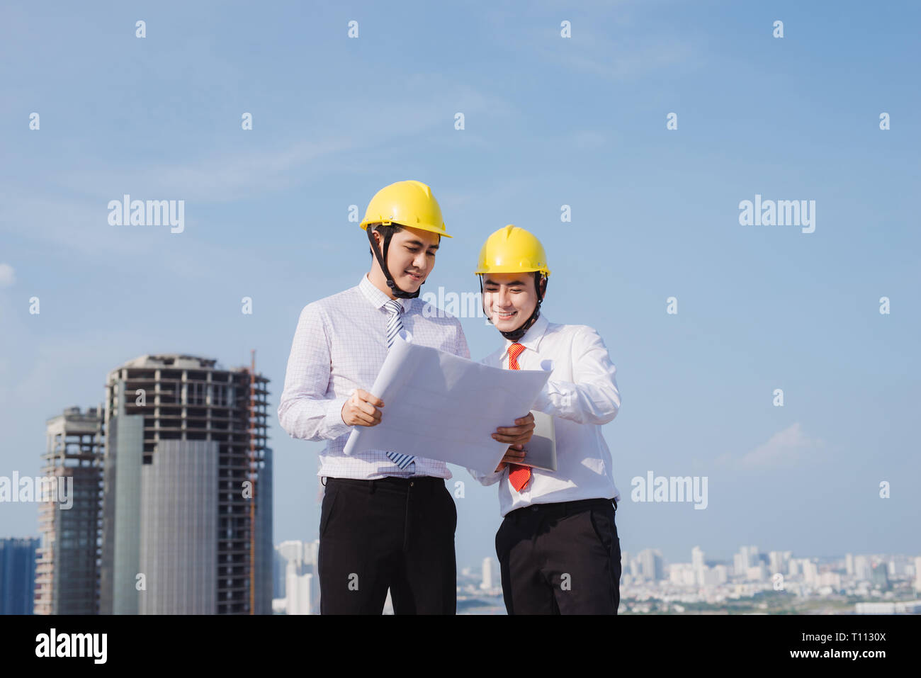 View of a Engineer and worker watching blueprint on construction site ...