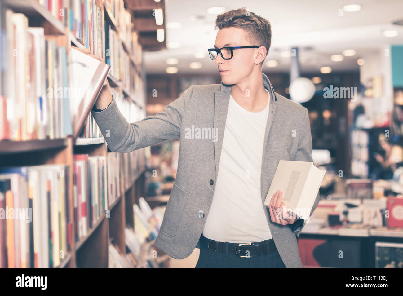 Young guy choosing books read hi-res stock photography and images - Alamy