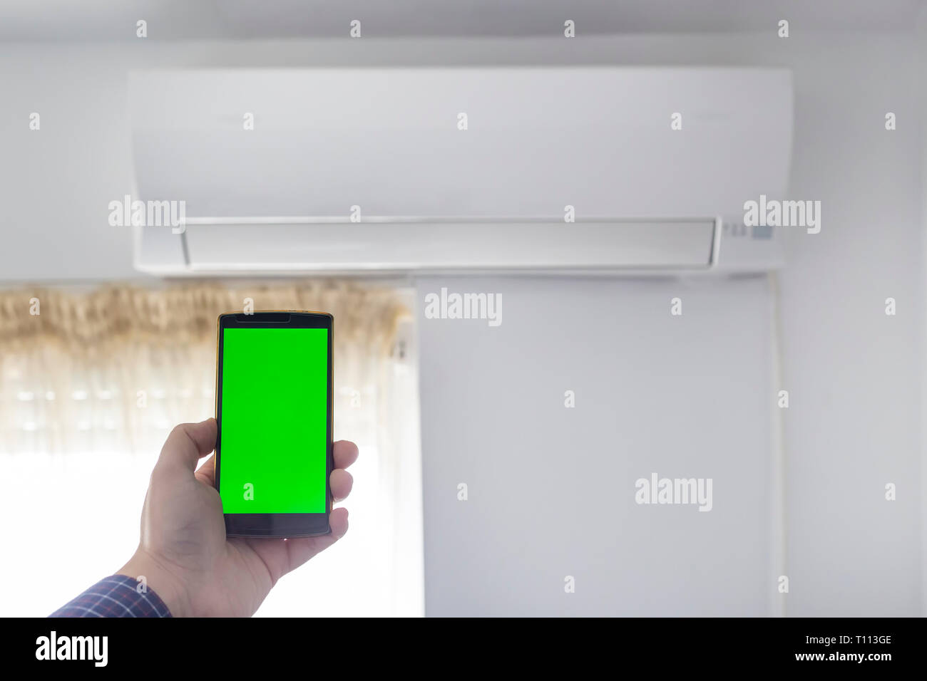 Air conditioner smartphone remote control concept. Hand holding a phone ...