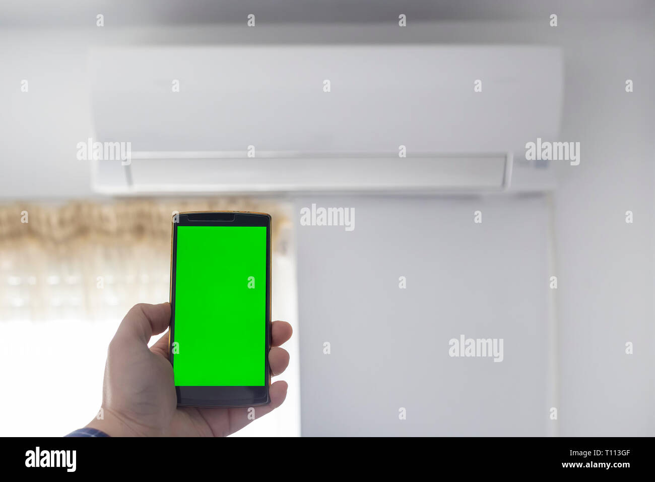 Air conditioner smartphone remote control concept. Hand holding a phone ...