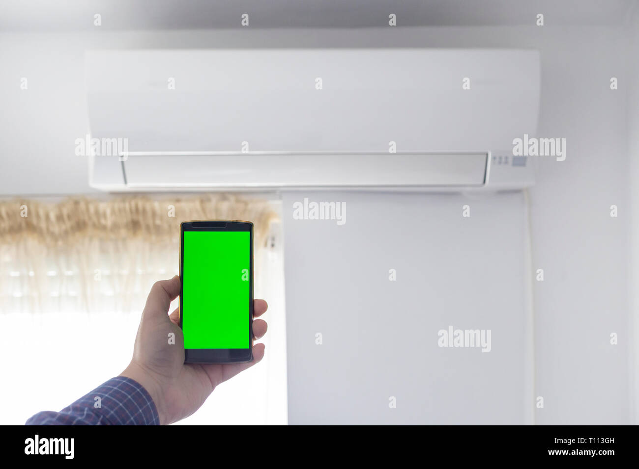 Air conditioner smartphone remote control concept. Hand holding a phone ...