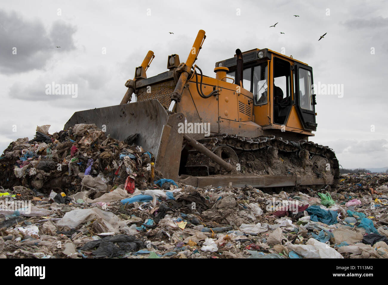 Bulldozer working on mountain of garbage in landfill Stock Photo - Alamy