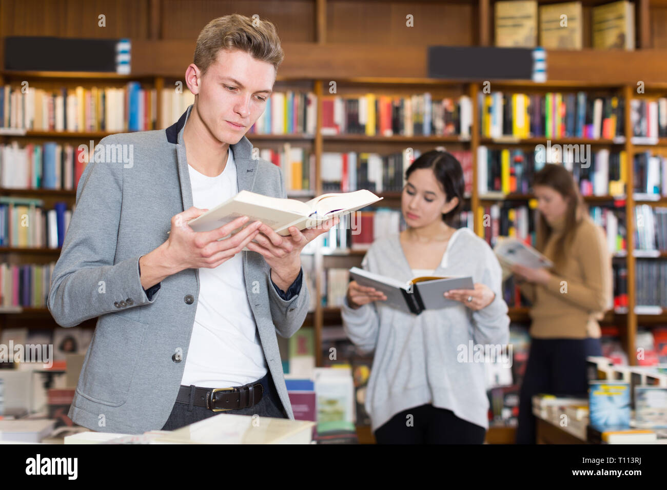Young guy reading interesting books in bookshop Stock Photo - Alamy