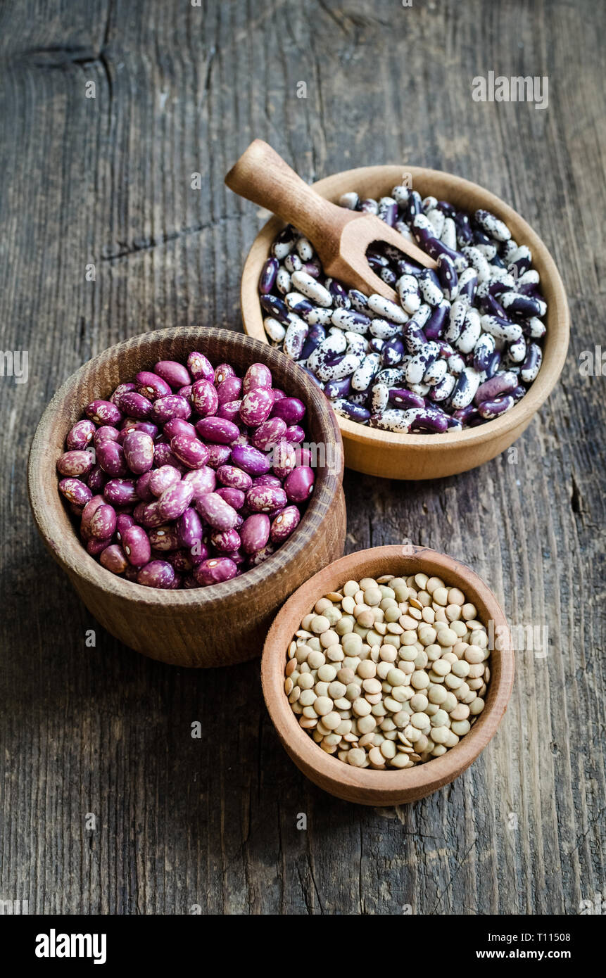 Assortment of dry organic beans and lentils in bowls on rustic wooden ...