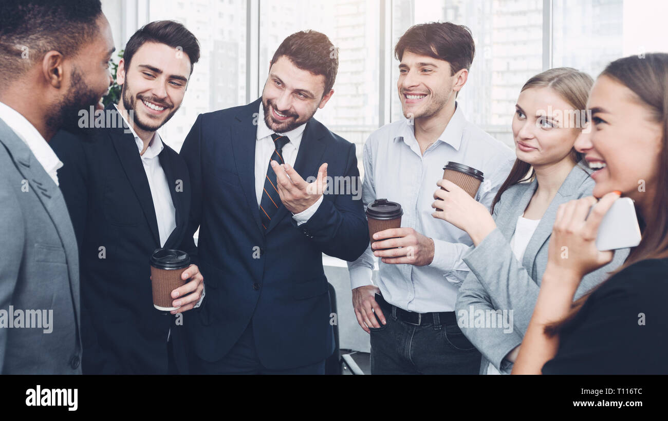 Happy colleagues talking, having coffee break in office Stock Photo - Alamy