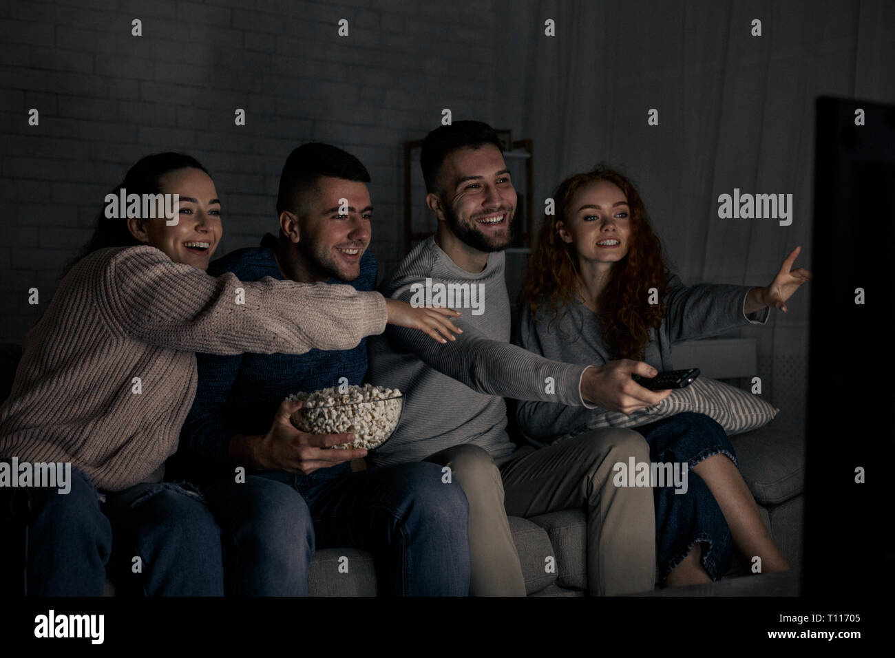 Happy friends watching TV and switching channels Stock Photo - Alamy