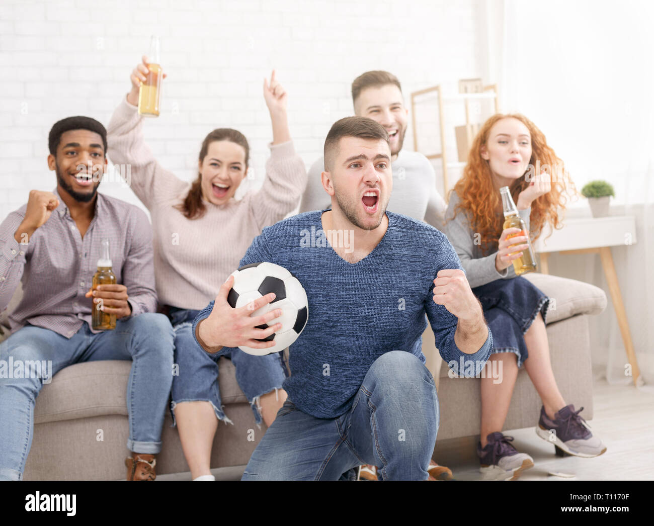 Emotional football fans watching match on tv Stock Photo - Alamy