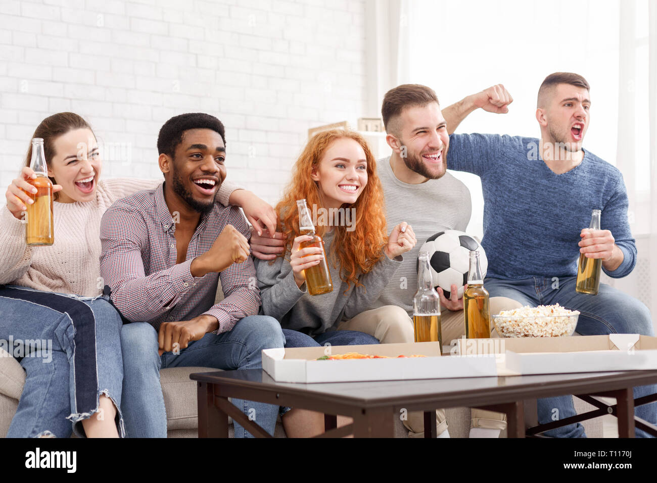 Excited football fans watching soccer on tv Stock Photo - Alamy