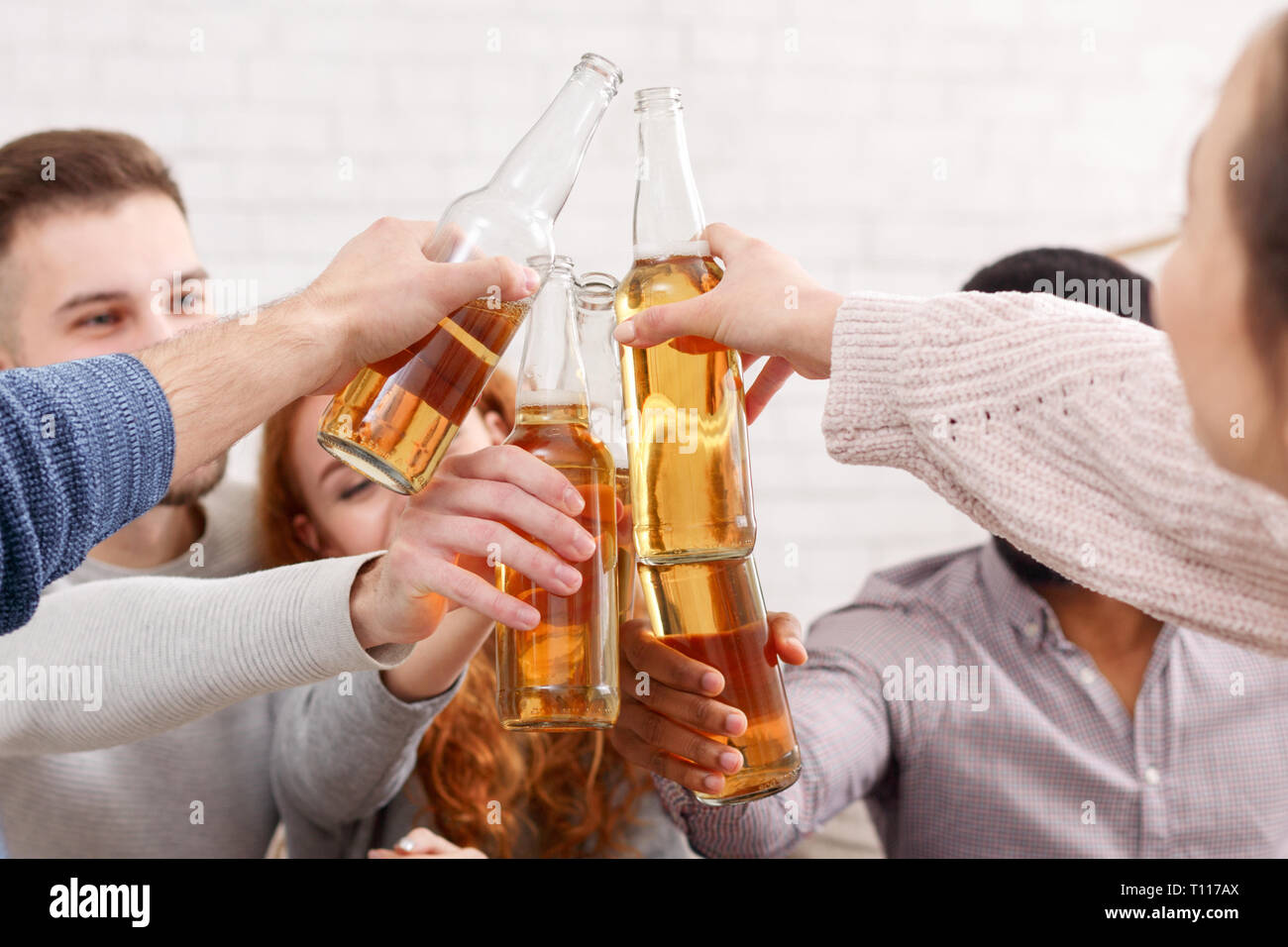 Celebrate meeting. Friends clinking beer bottles at home Stock Photo ...