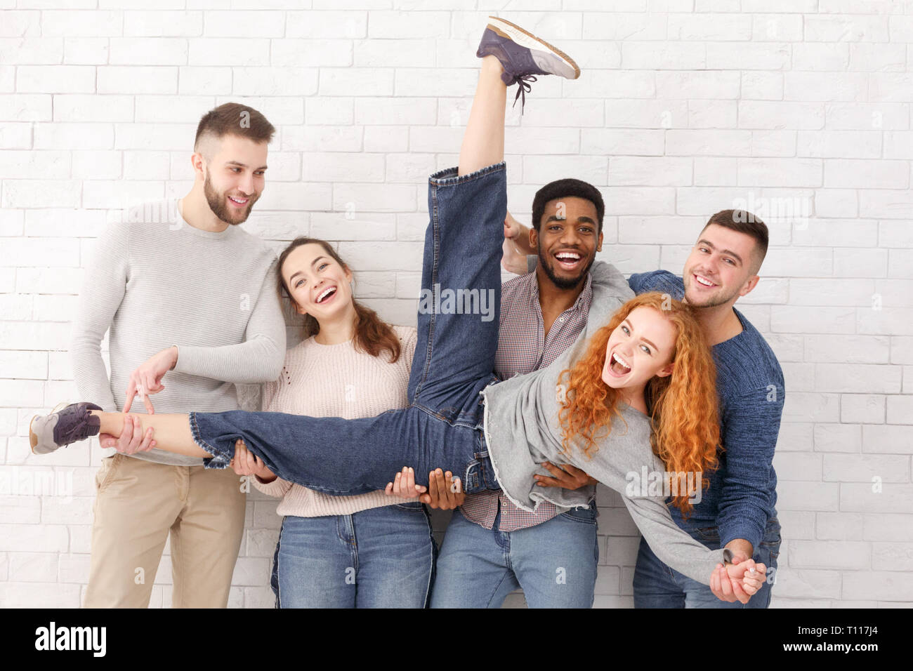 Friends having fun over white brick wall Stock Photo - Alamy
